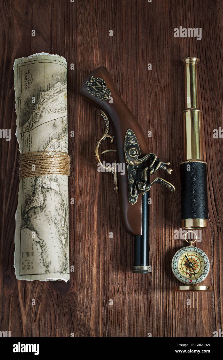 Collection with old pistol, map, compass and telescope on a wooden ...