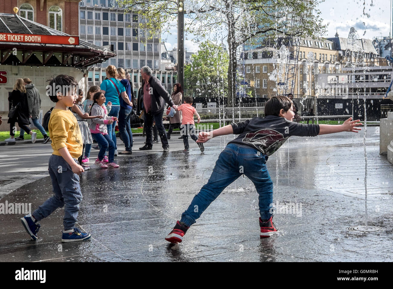 Two boys play happy fun in a fountain in London near Trafalgar square ...