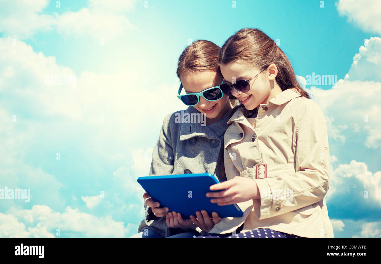 happy girls with tablet pc computer over blue sky Stock Photo - Alamy