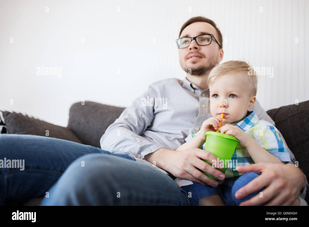 father and son drinking from cup and at home Stock Photo - Alamy