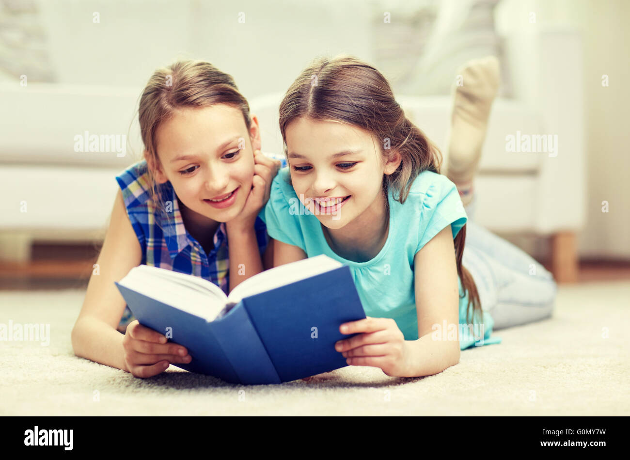two happy girls reading book at home Stock Photo - Alamy