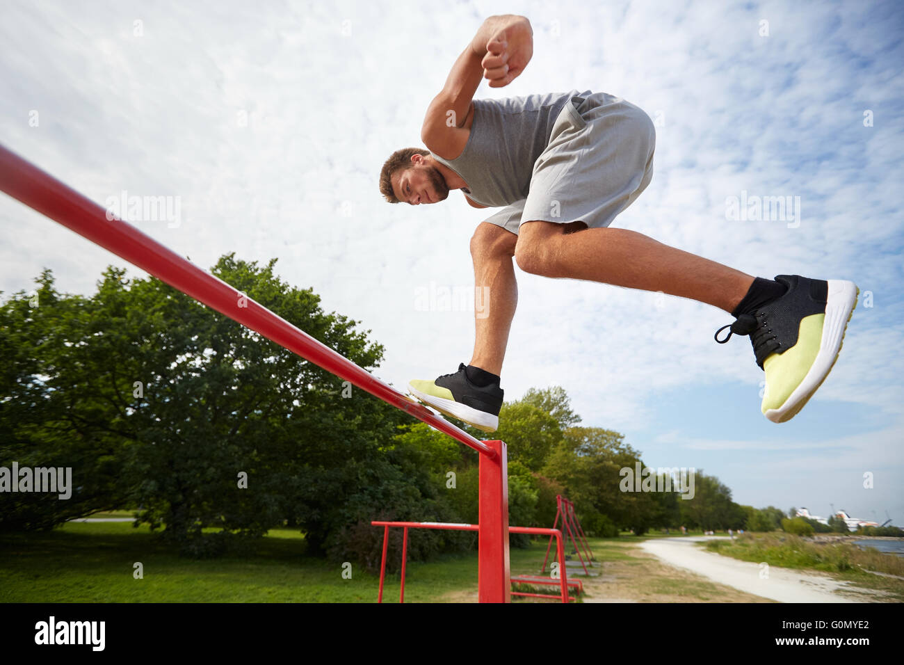 young man jumping on horizontal bar outdoors Stock Photo - Alamy