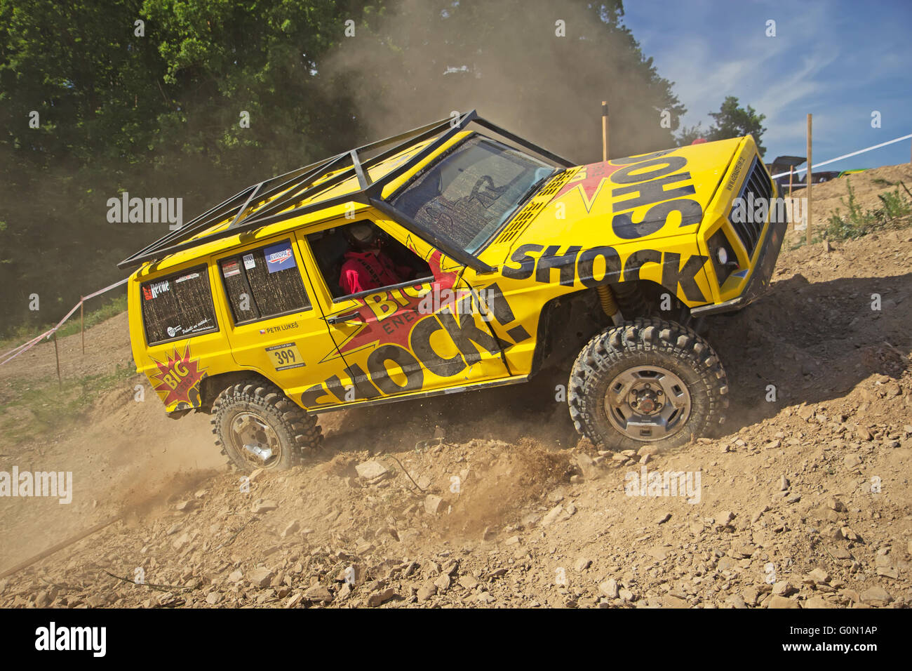 Yellow off-road car is hitting a steep hill in the difficult terrain ...