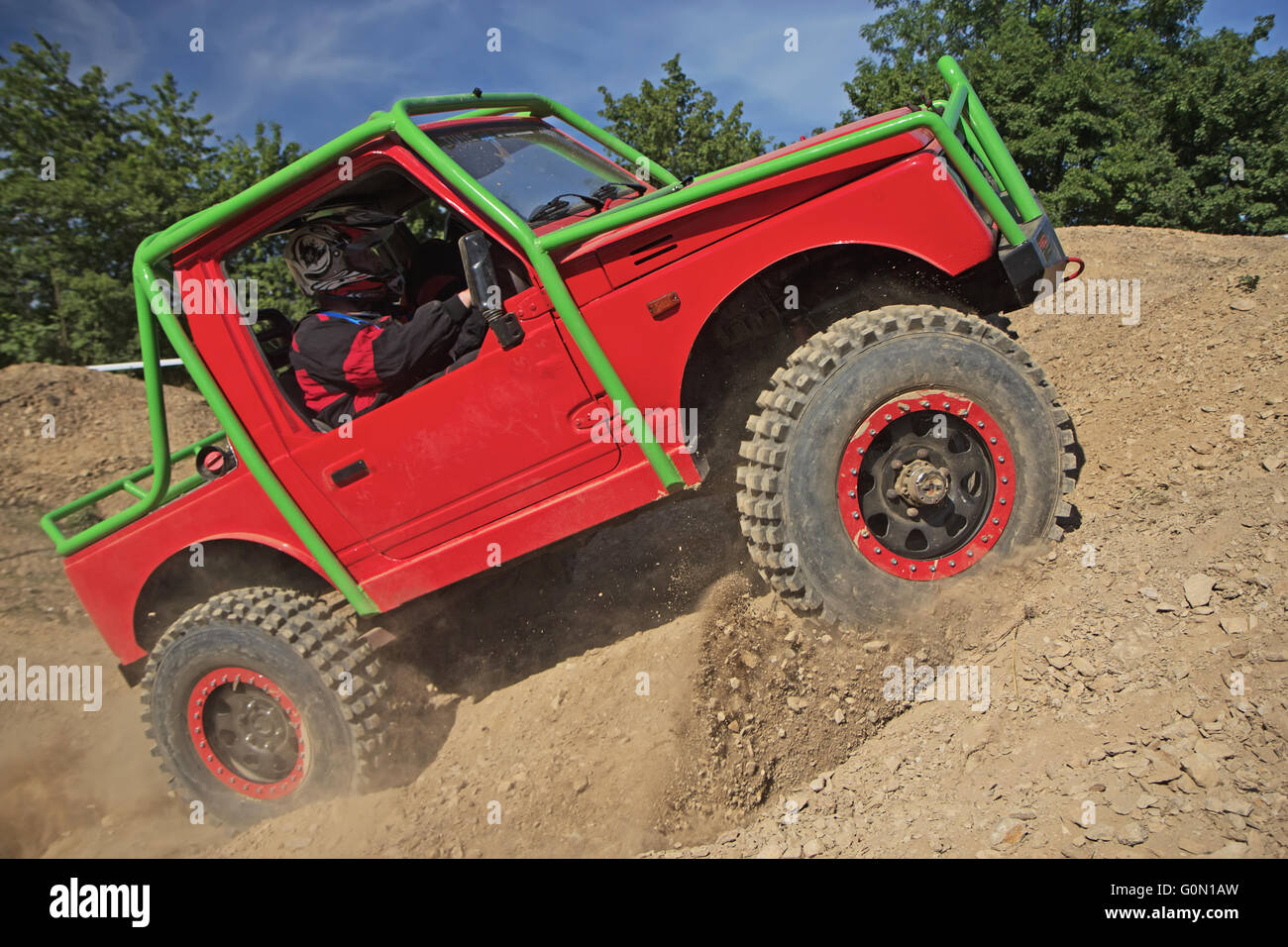 Small red off road car is hitting a steep hill in the difficult terrain ...