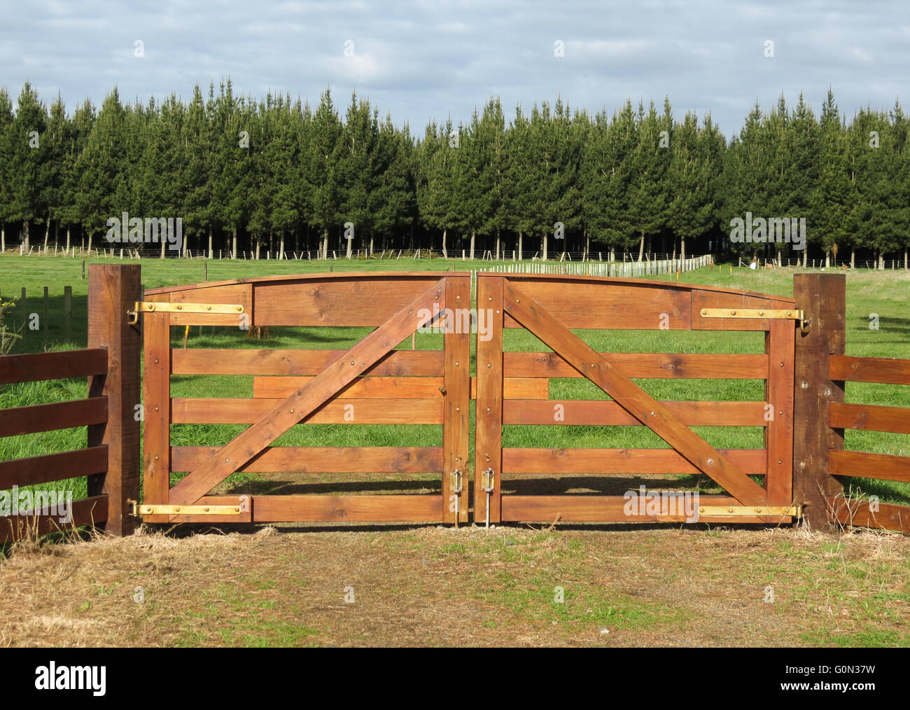 Nice strong brown wooden farm gateway, with lush green grass behind it ...