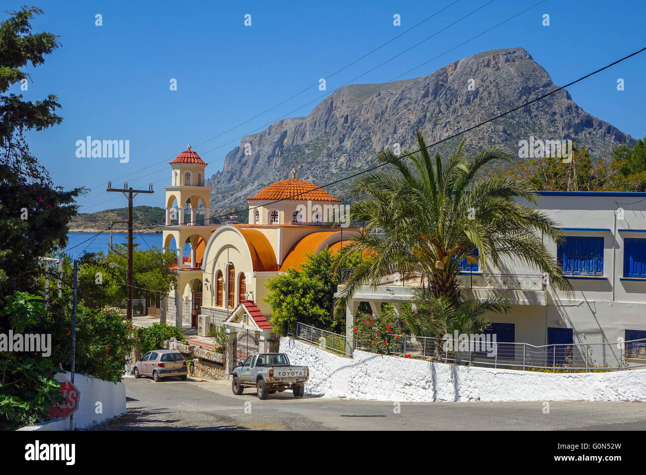 Orange roofed Greek Orthodox church with palm tree, white walls and ...