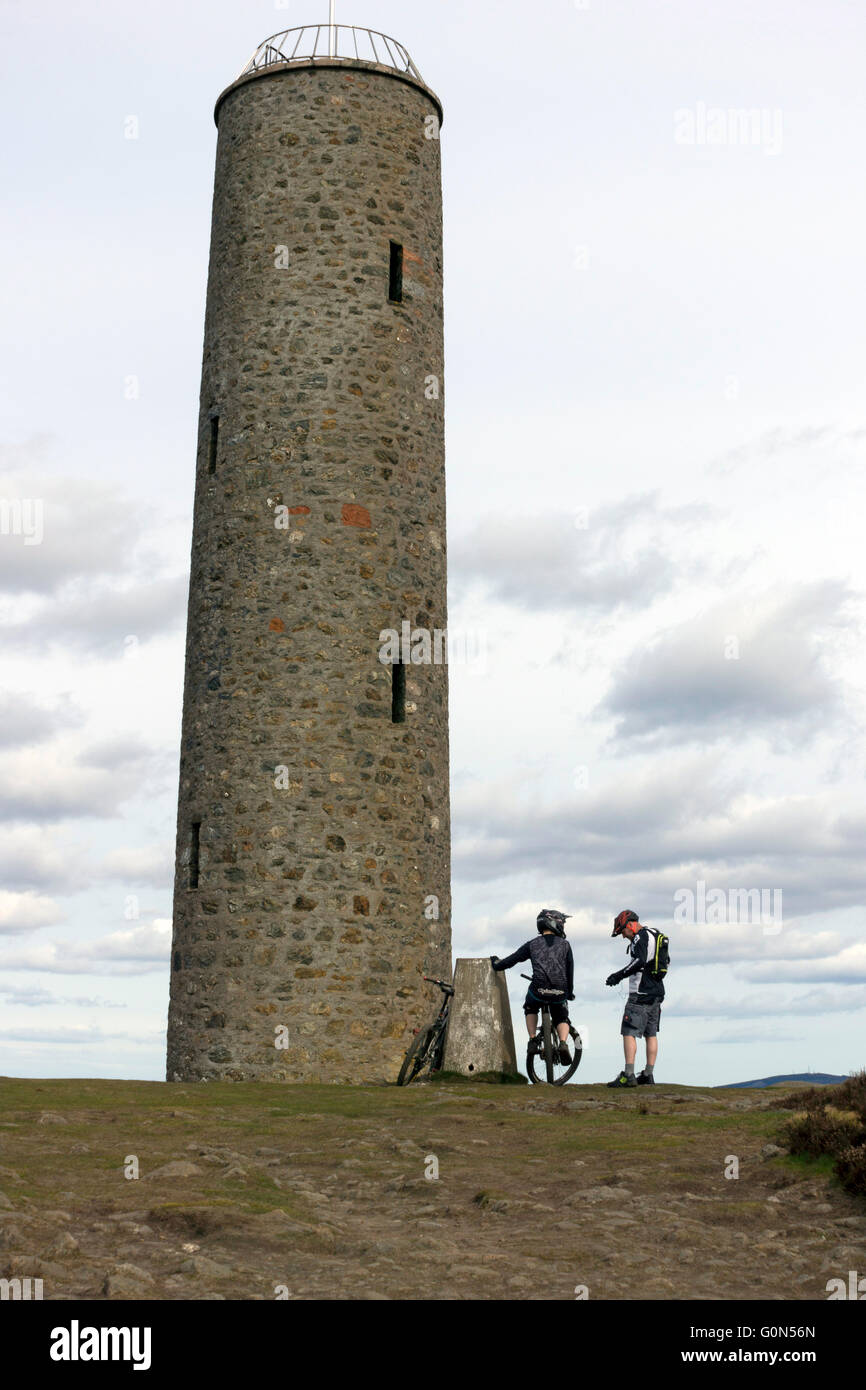 Two cyclists resting by the tower at the top of Scotly Hill, near ...