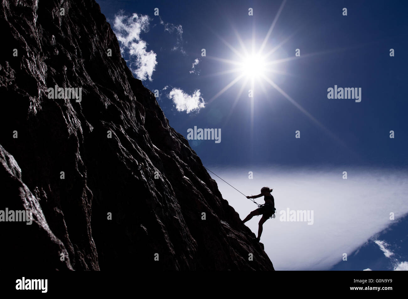Woman in silhouette rappelling down a rock face Stock Photo - Alamy