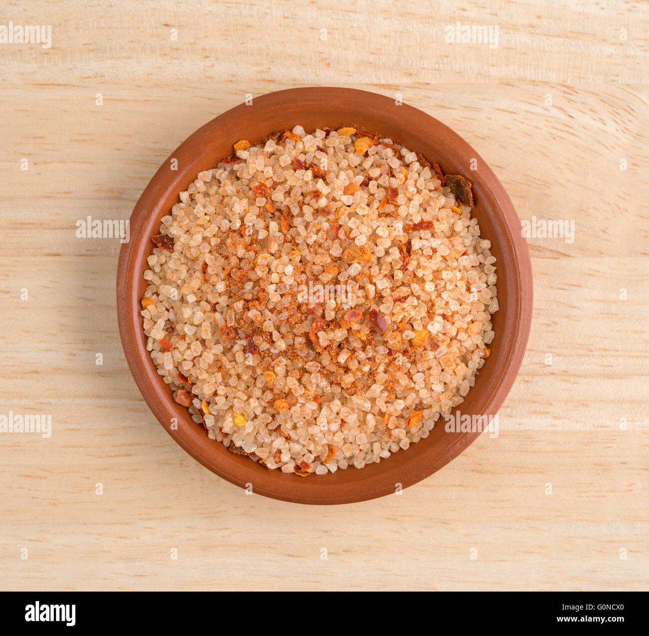 Top view of a small dish filled with ground salt, red chili peppers and ...