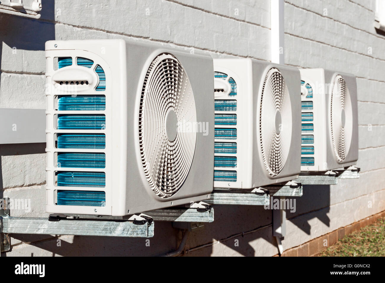 Three newly installed air conditioning units mounted on exterior wall ...