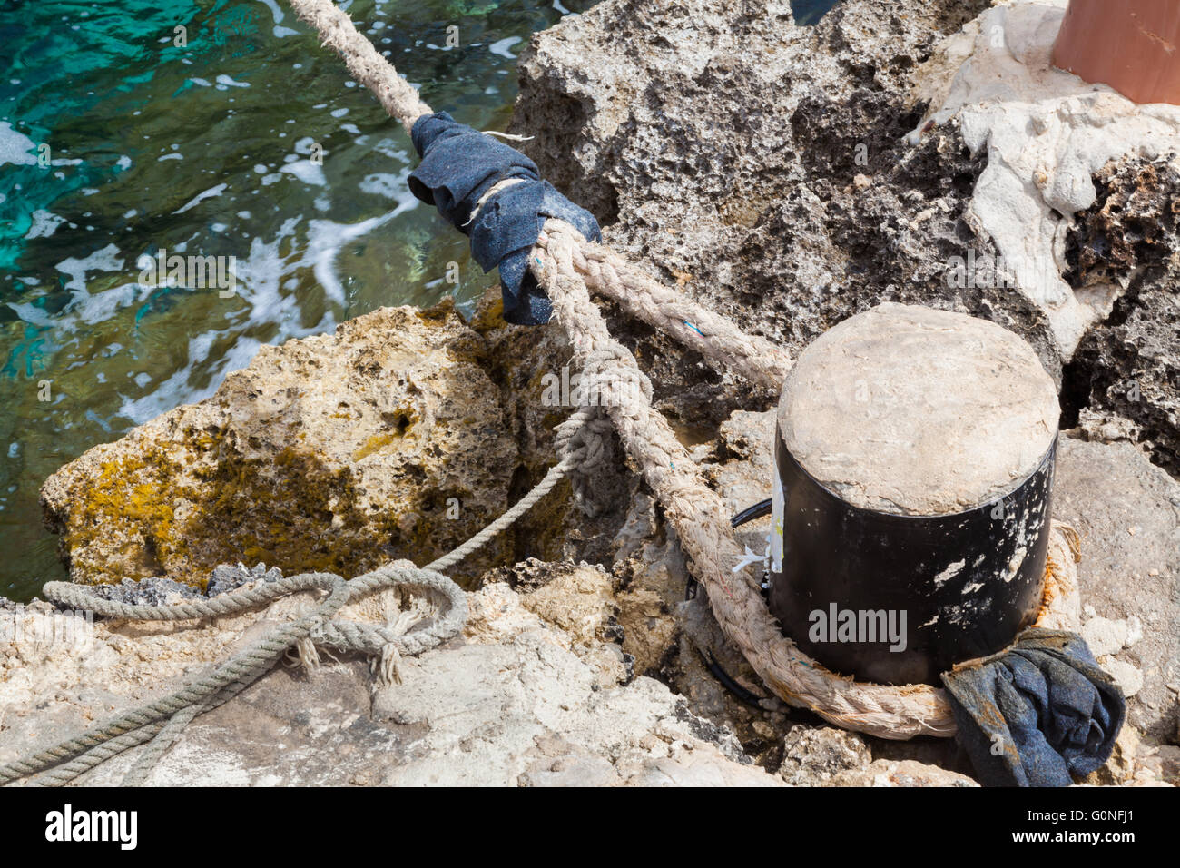 Weathered boat rope hanged to a stone Stock Photo - Alamy