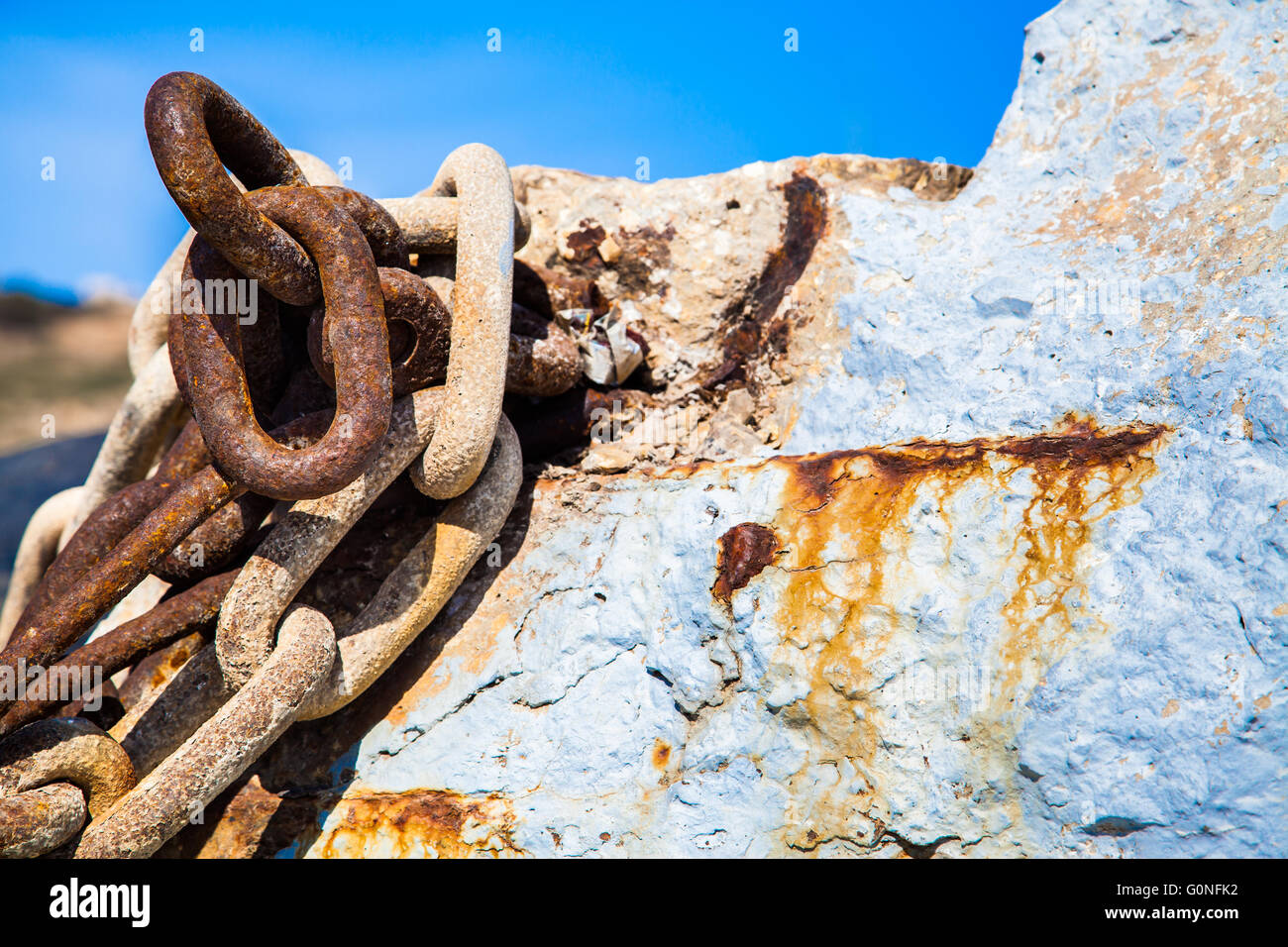 Rusty weathered chains hanged on sea rocks Stock Photo - Alamy