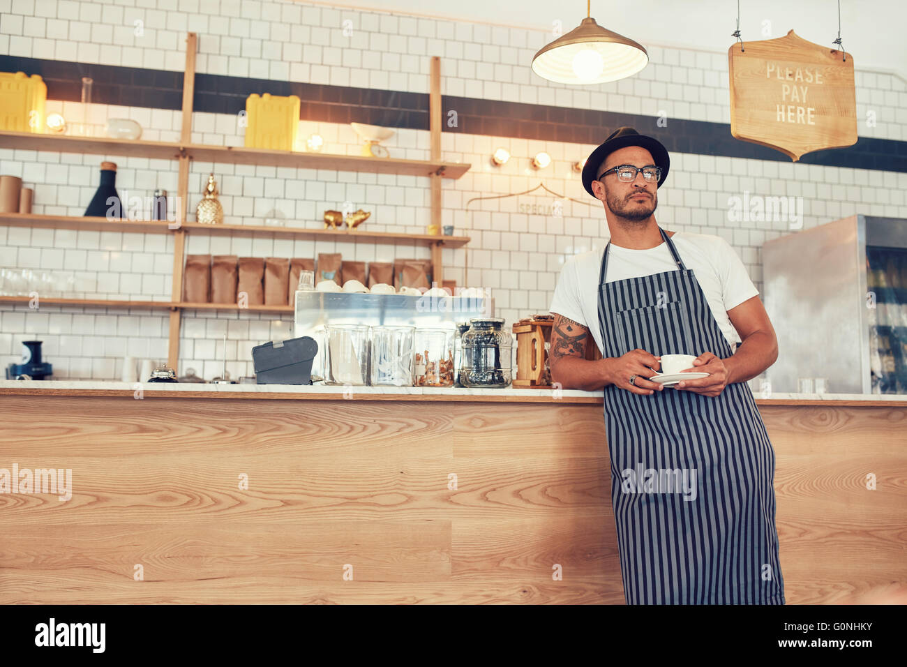 Portrait of young man working at a restaurant wearing an apron and hat ...