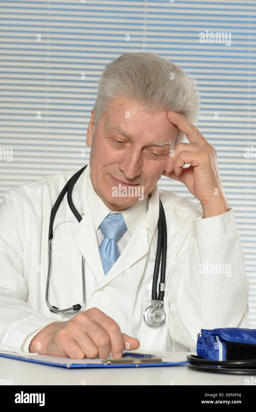 Elderly doctor at table Stock Photo - Alamy