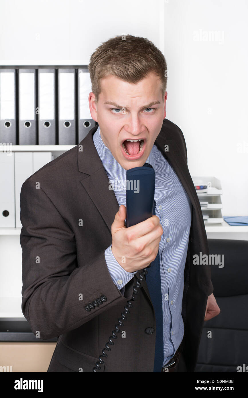 Young businessman is shouting into the phone while standing in the ...