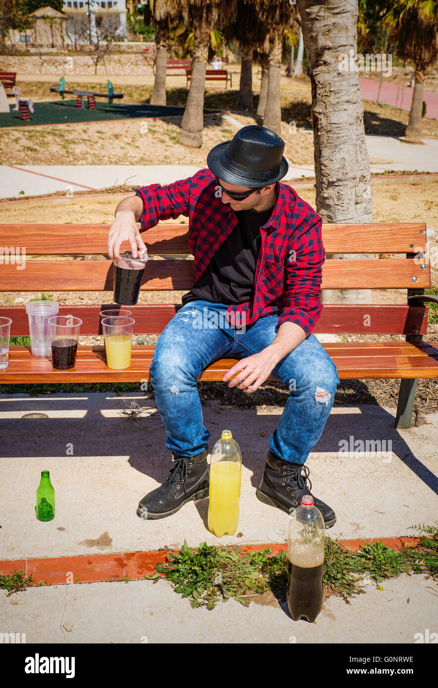 Guy getting heavily drunk on a park bench Stock Photo - Alamy