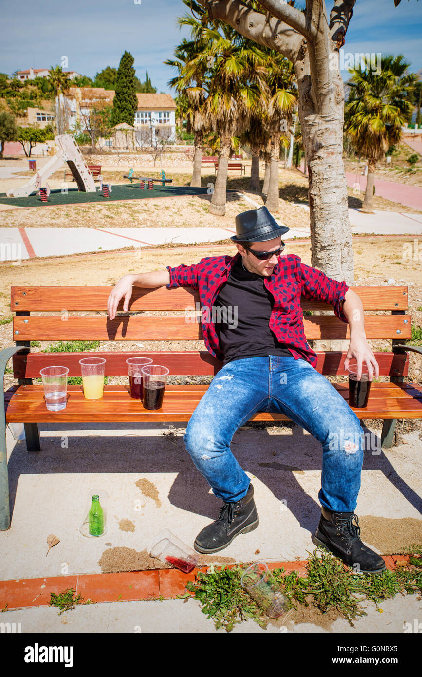 Guy getting heavily drunk on a park bench Stock Photo - Alamy