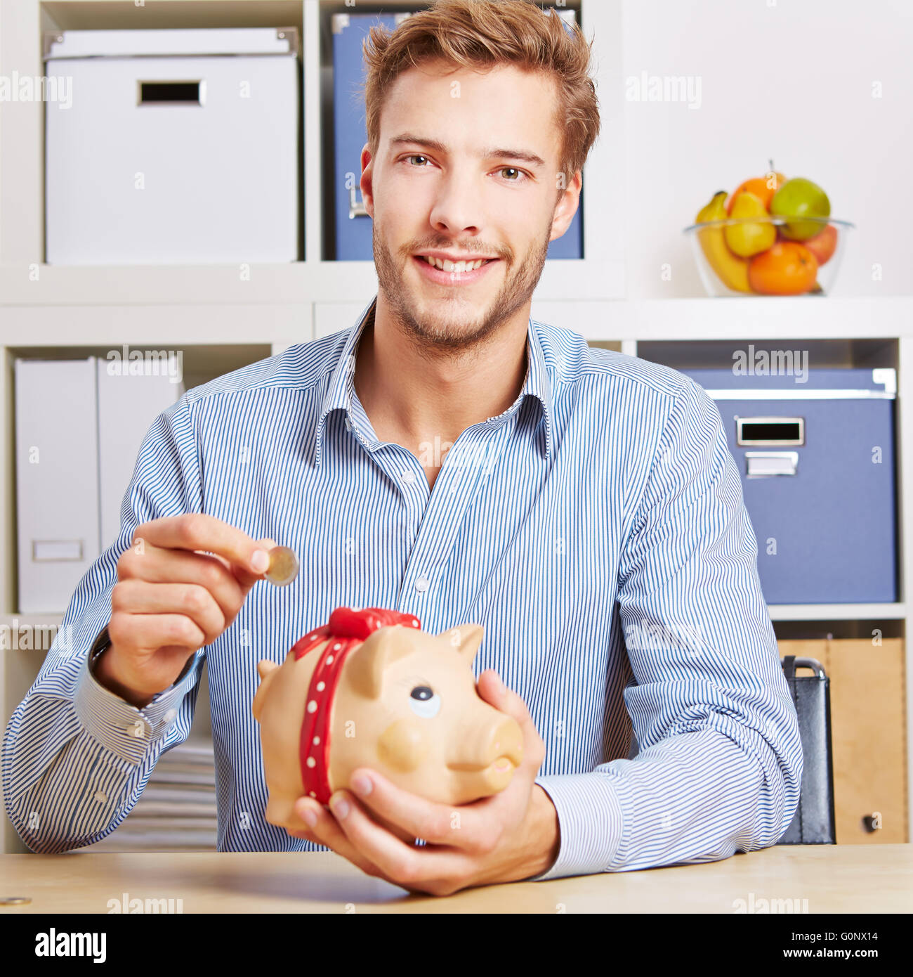 Smiling young man saving his Euro money in a piggy bank Stock Photo - Alamy