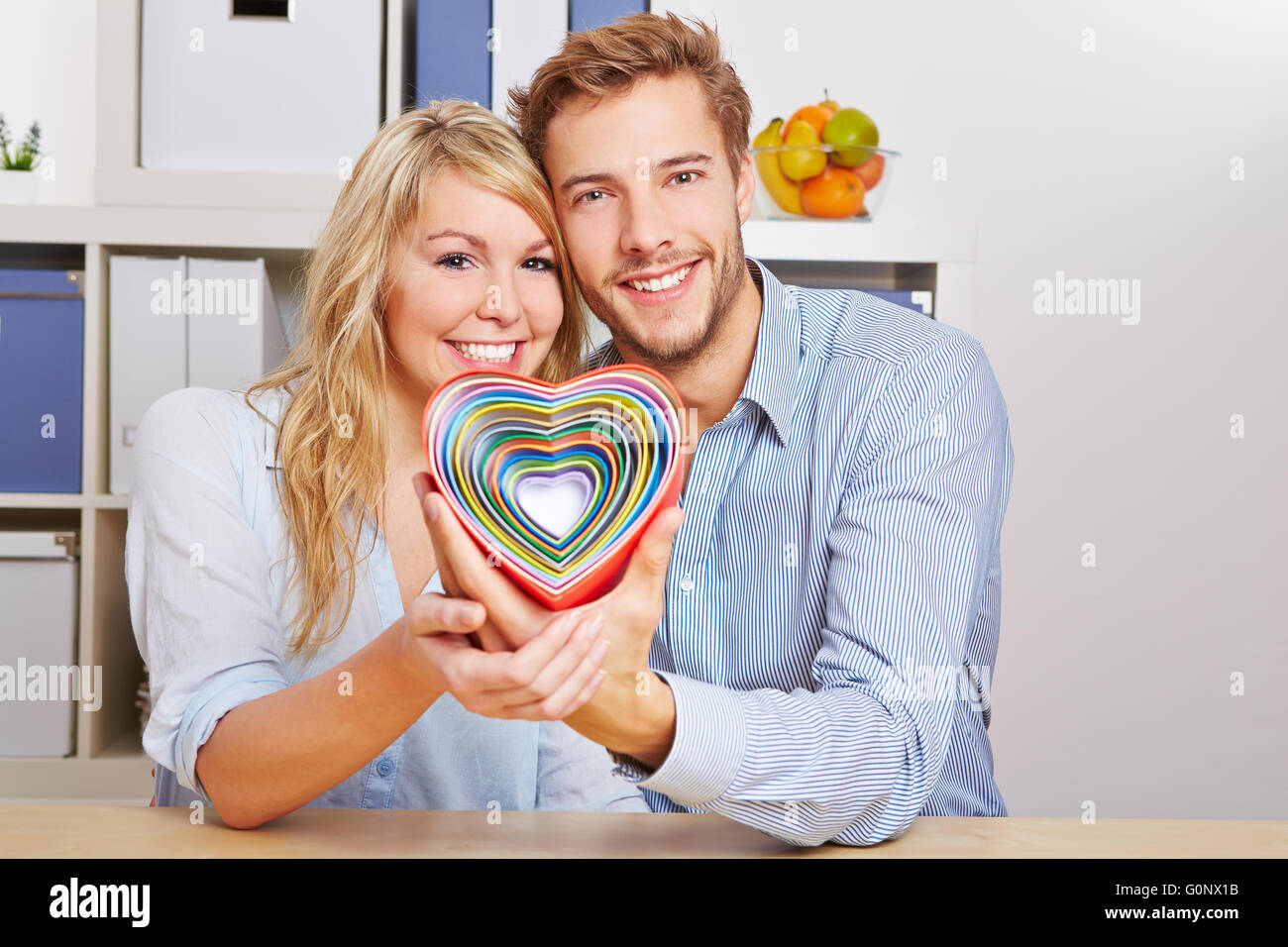 Happy attractive couple with many colorful hearts in a living room ...