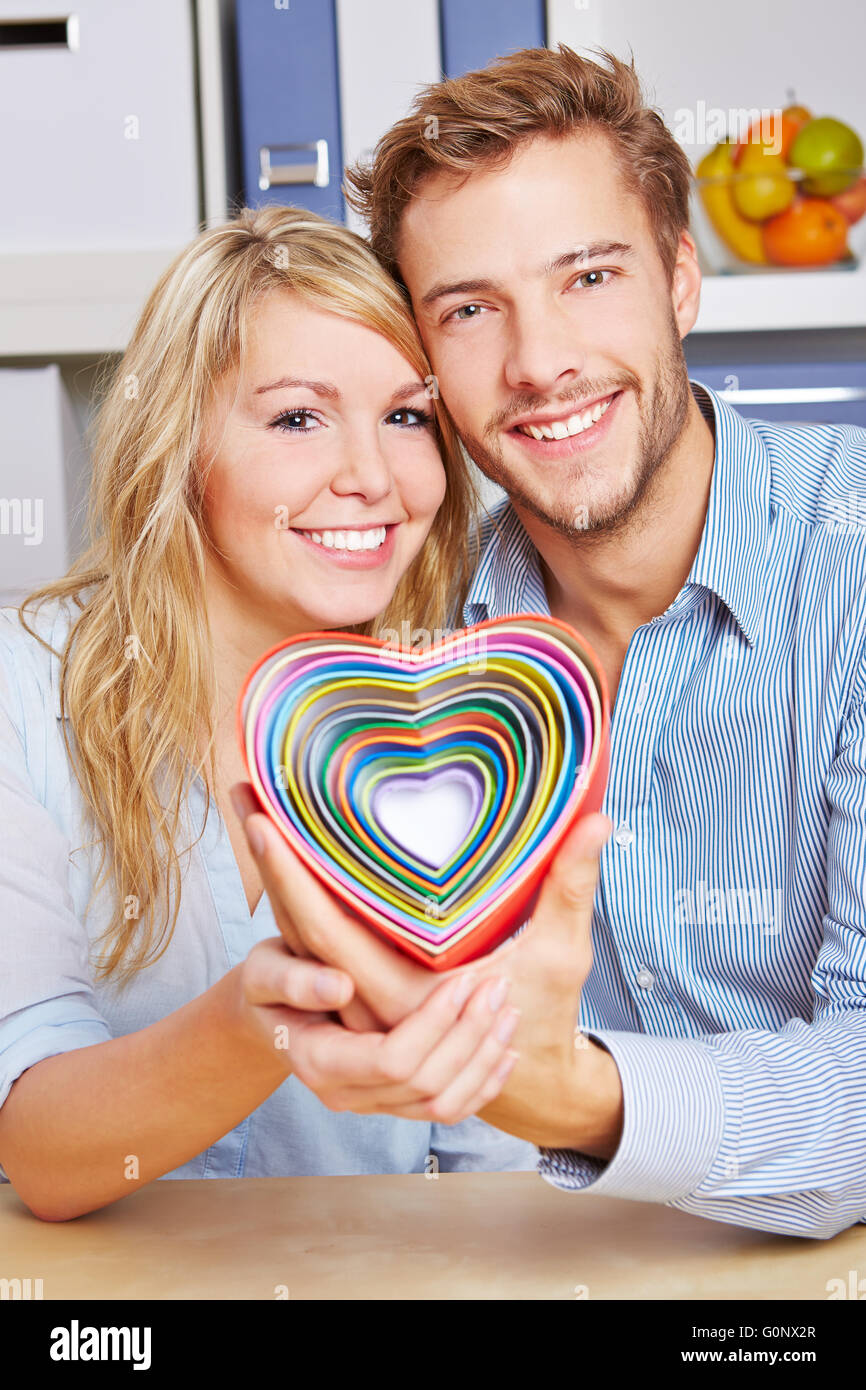 Smiling happy couple holding many colorful hearts in a living room ...