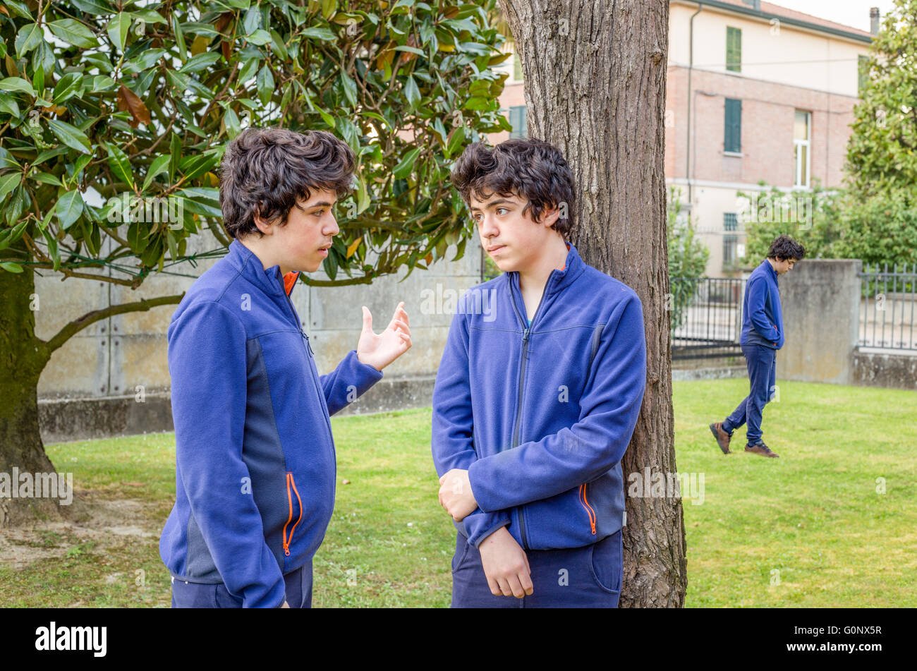 Boys who talk to each other in a garden while another is walking alone ...