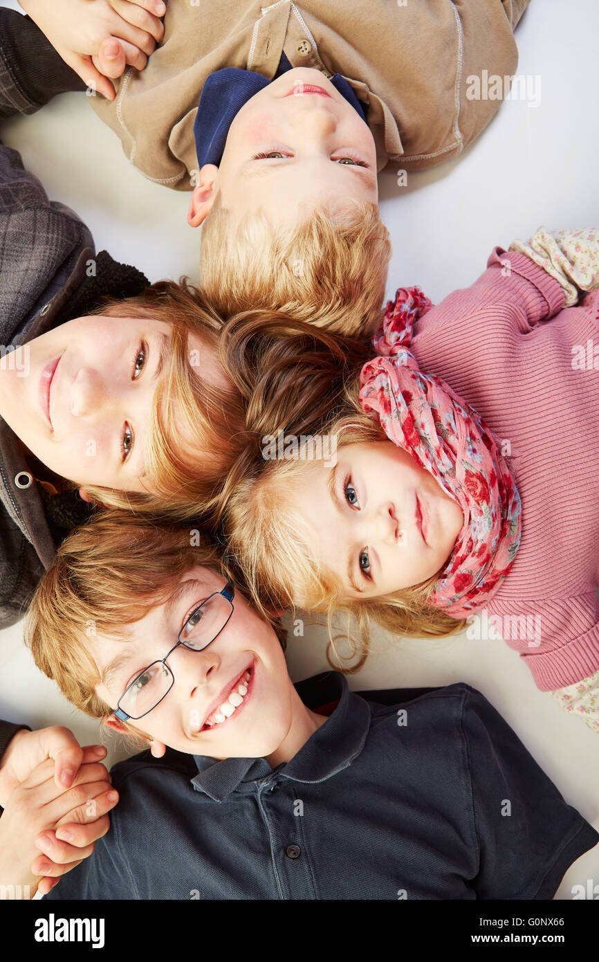 Four happy smiling children laying in a circle and looking up Stock ...