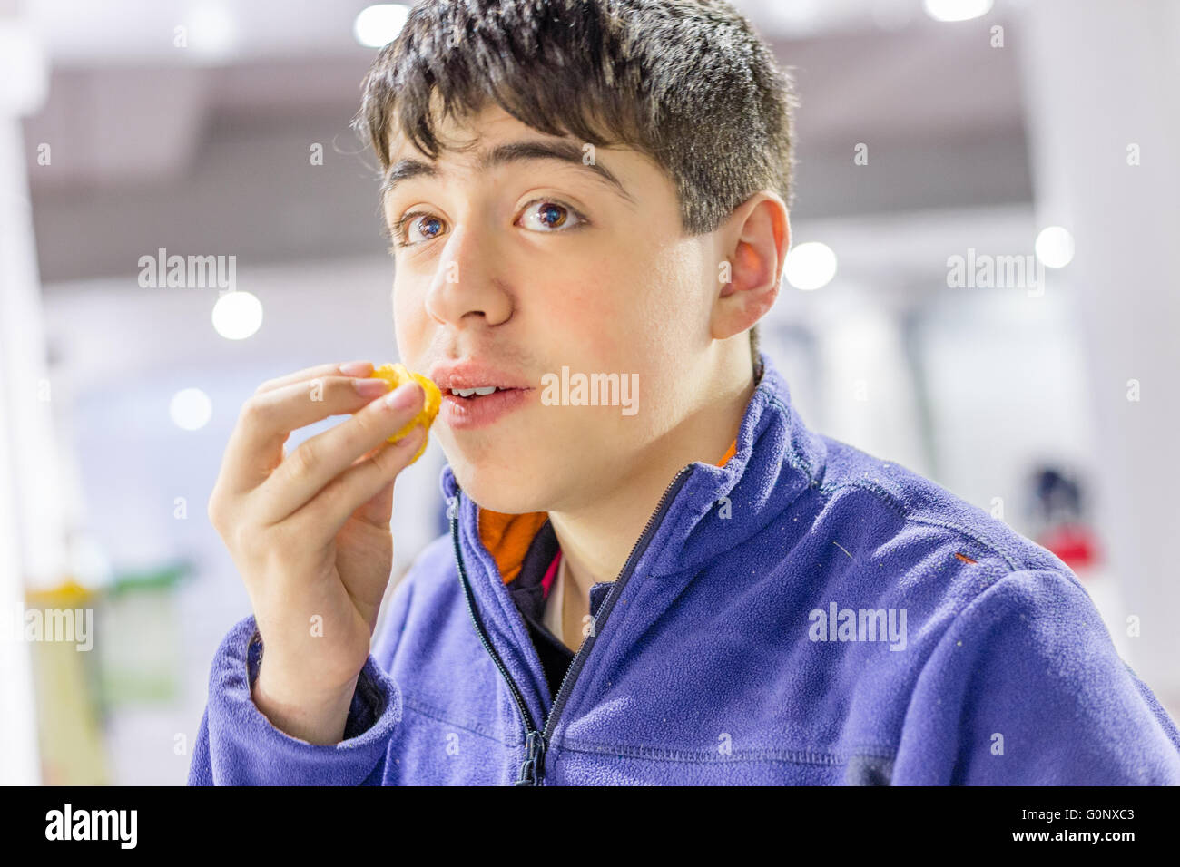 portrait of caucasian boy eating chips in the waiting room at the train ...