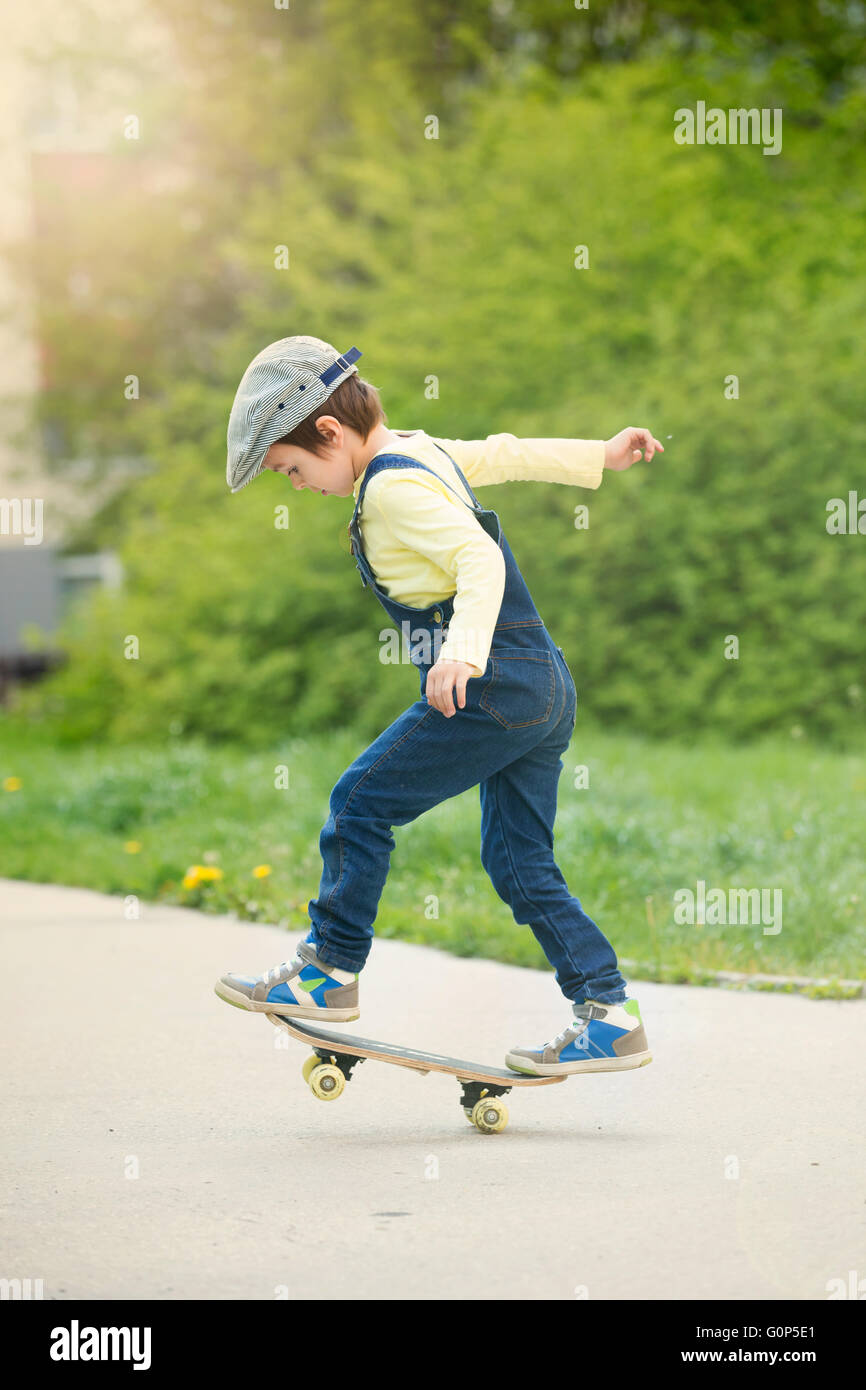 Adorable preschool child, skateboarding on the street, late spring ...