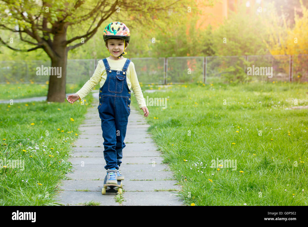 Adorable preschool child, skateboarding on the street, late spring ...