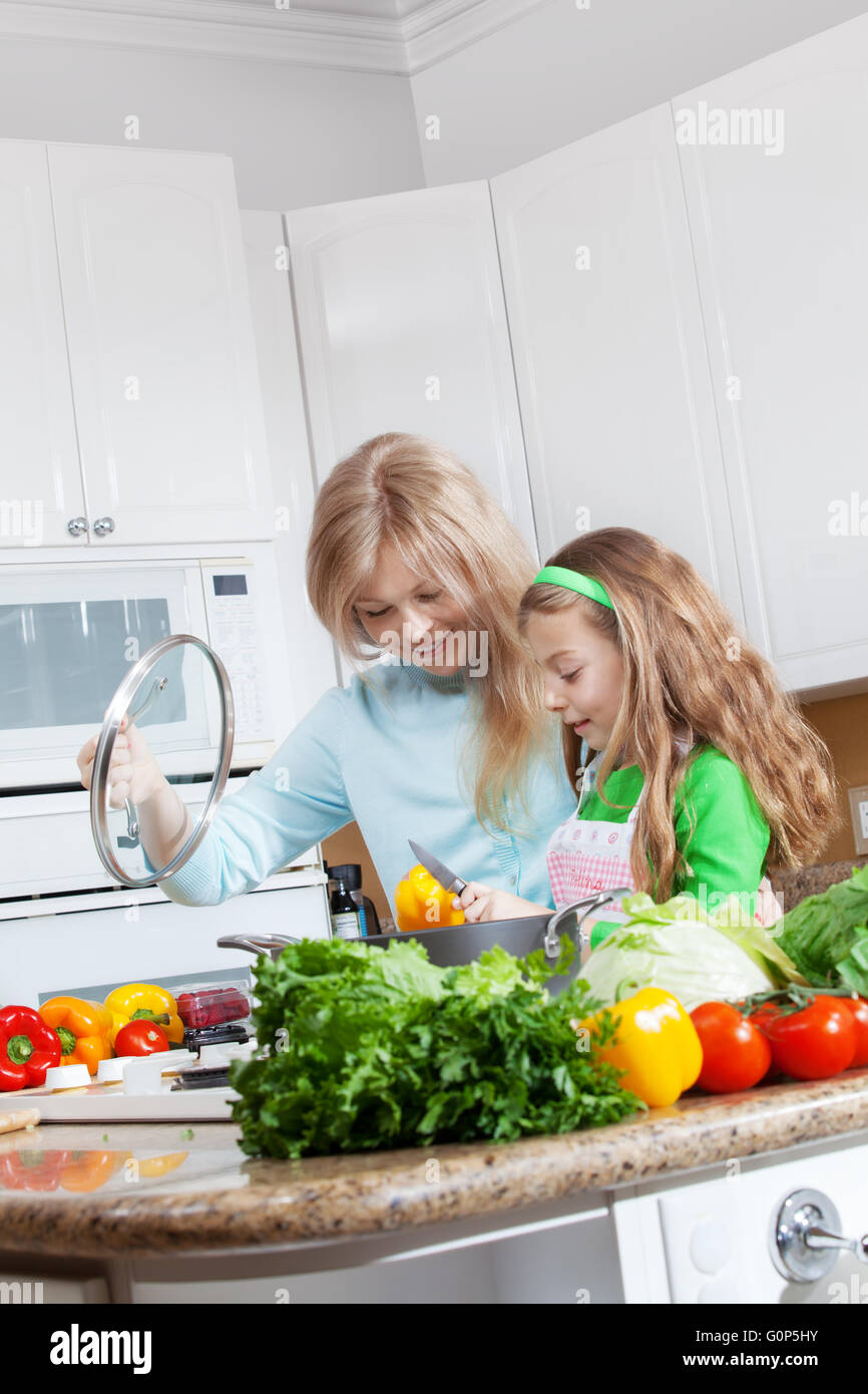 view of young beautiful girl cooking at the kitchen with her mama Stock ...