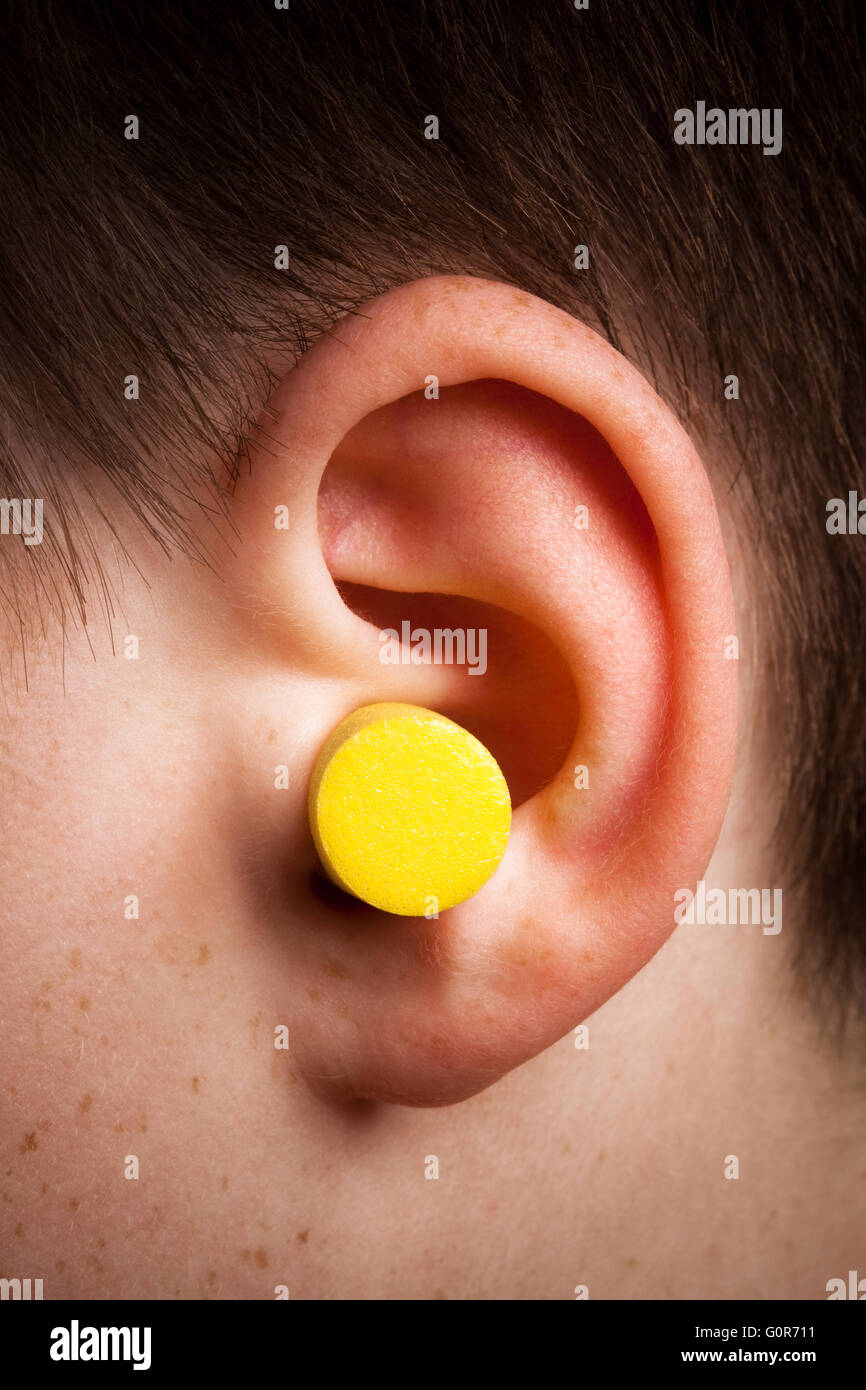 yellow earplug into the ear close up Stock Photo - Alamy