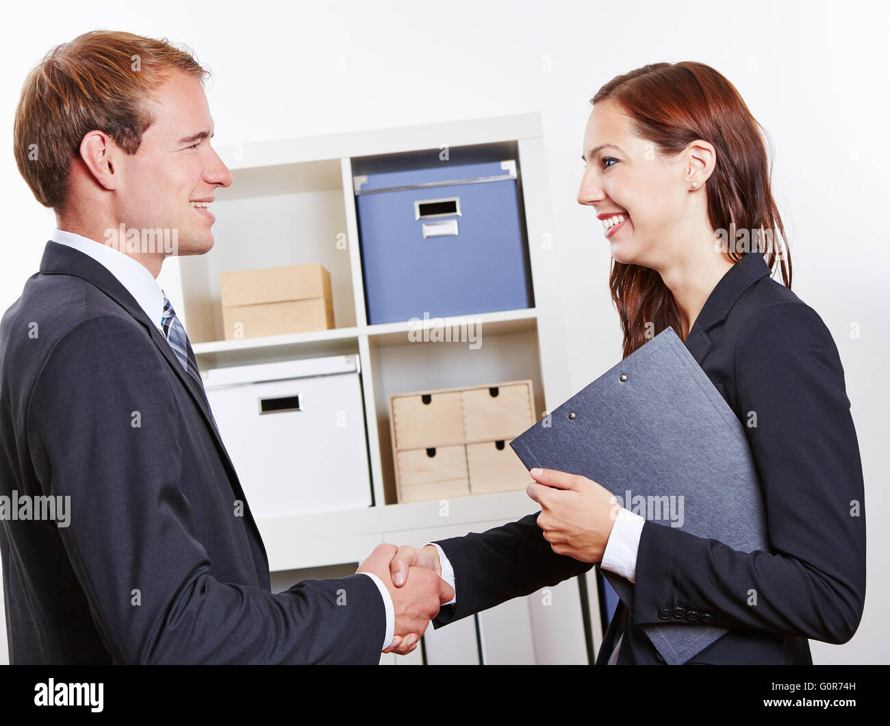 Two happy business people shaking their hands in the office Stock Photo ...