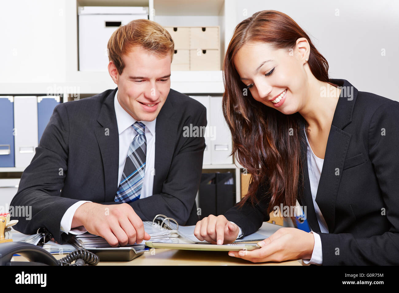 Two business people working with tablet computer at the desk in the ...