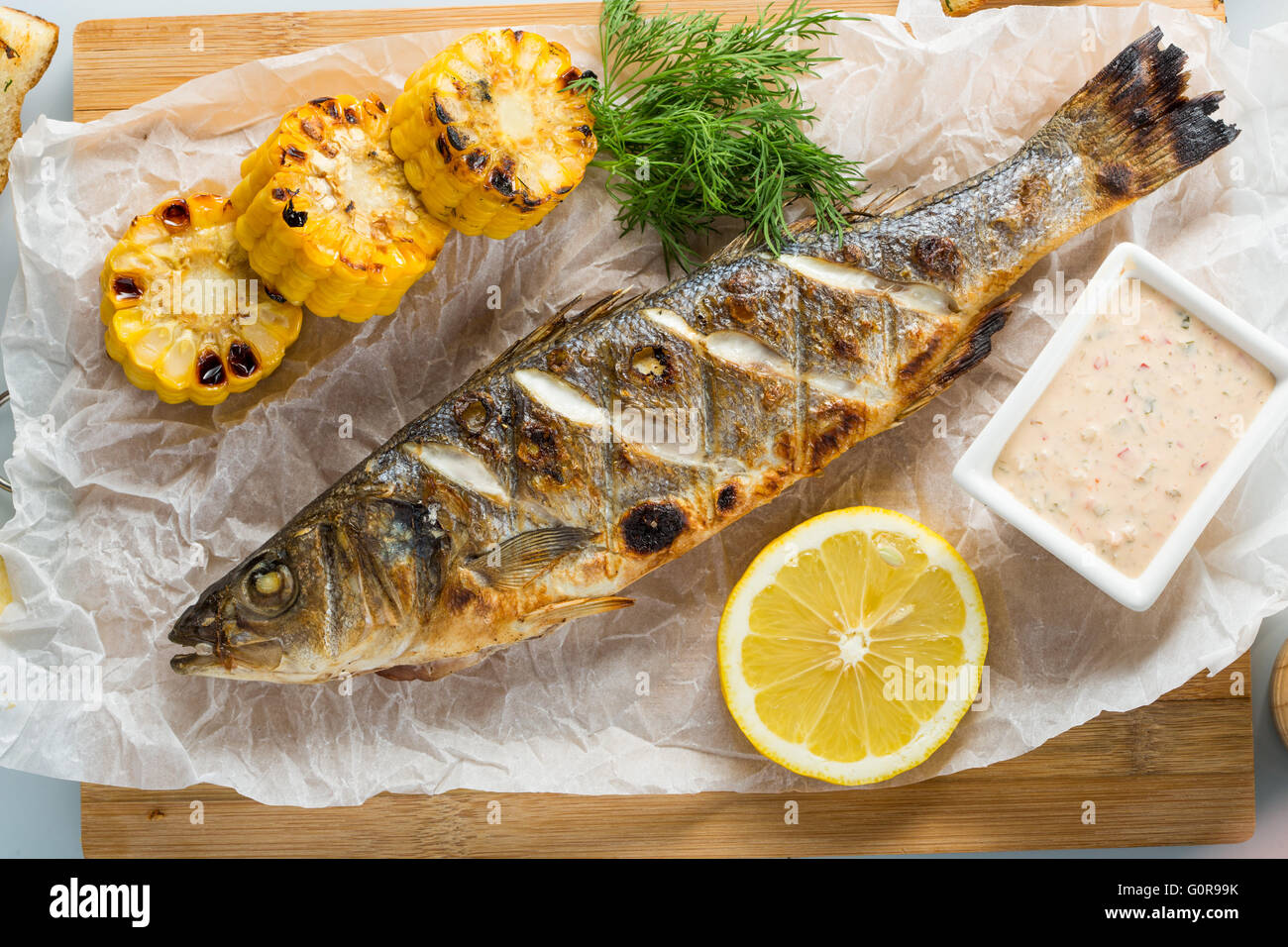 fish baked on the grill. with potatoes and lemon Stock Photo - Alamy
