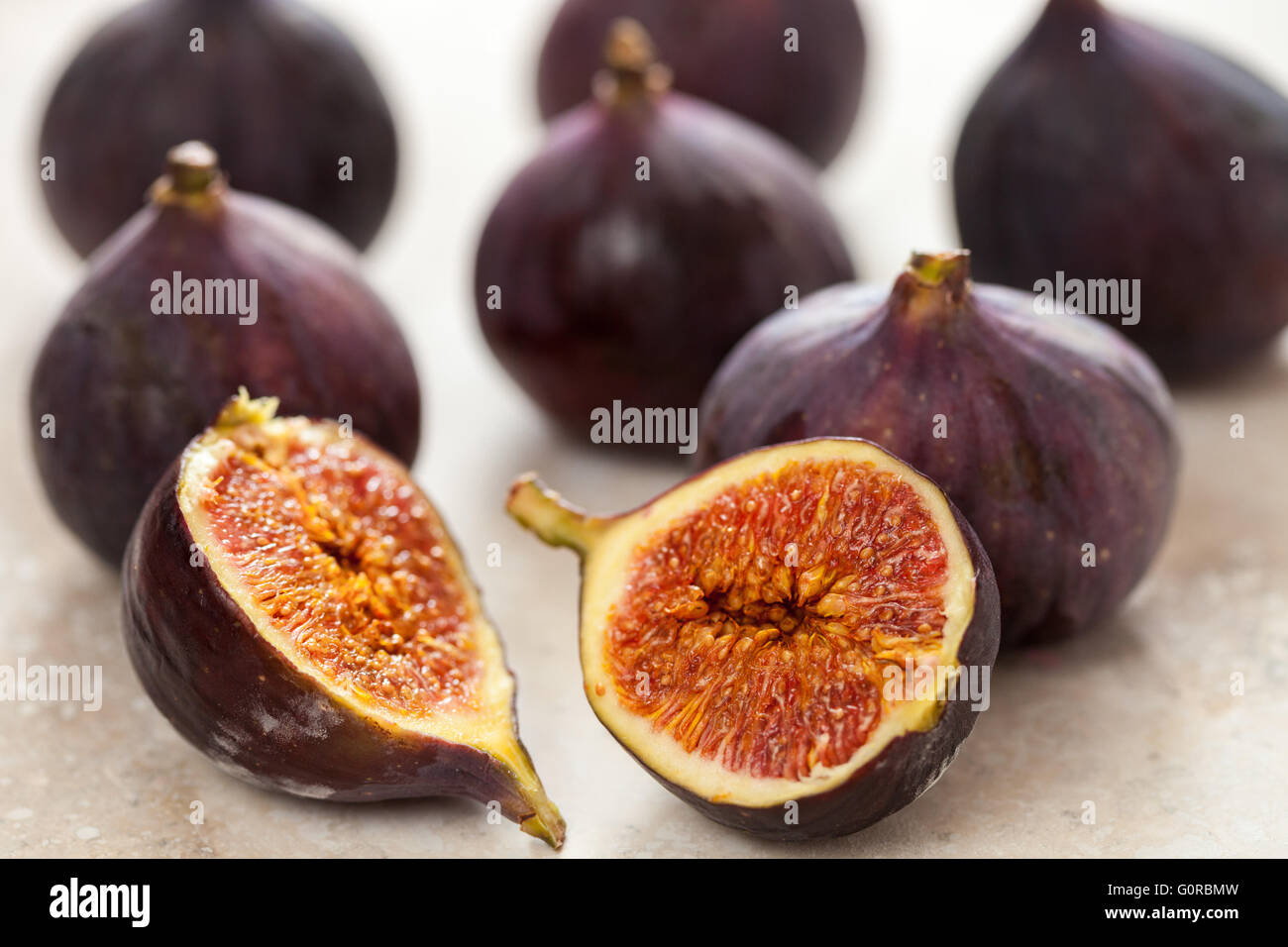 Close-up of a fig sliced in half on a ceramic tile surface. several ...