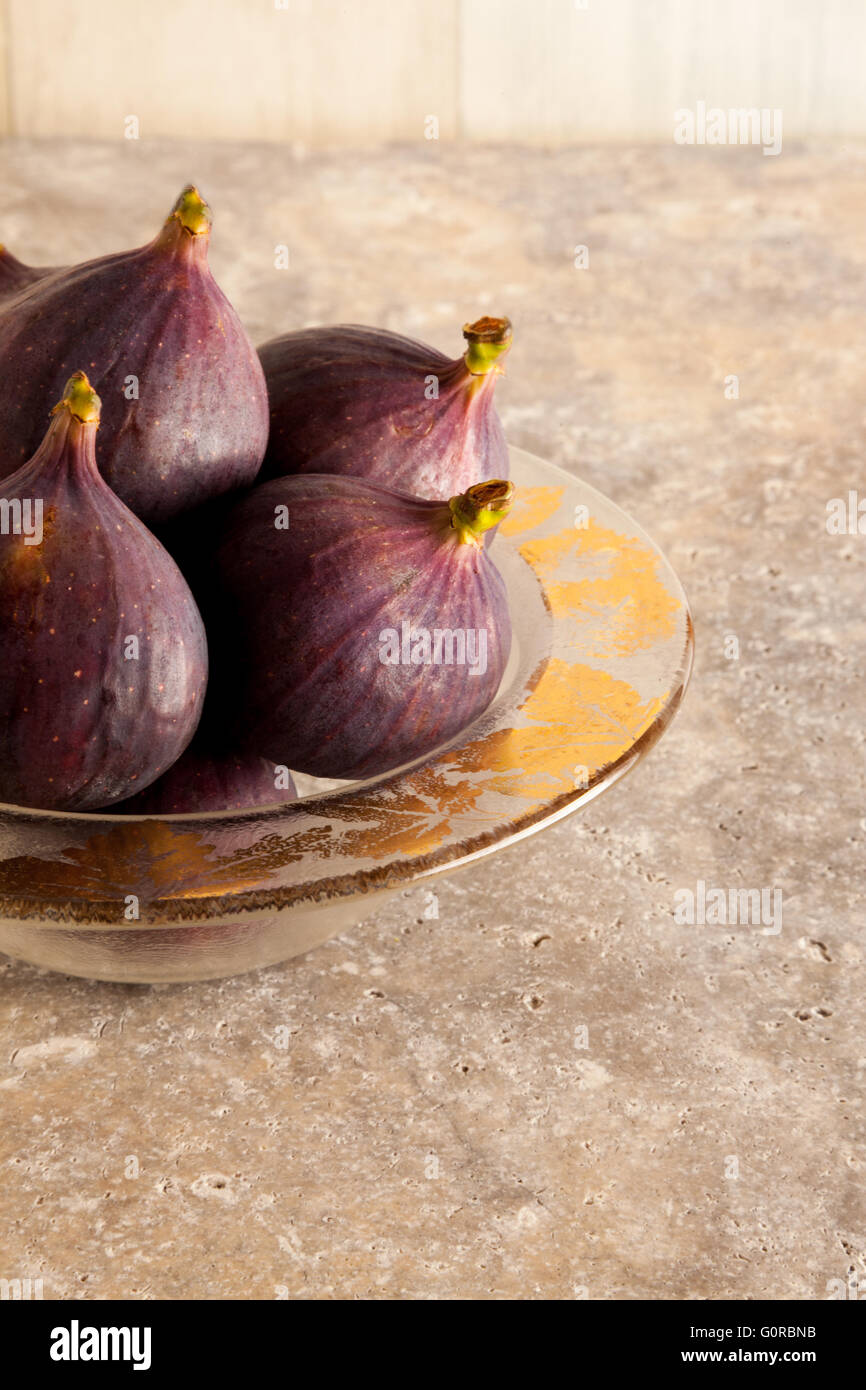 Whole fresh figs in a glass bowl on a ceramic tile surface Stock Photo ...