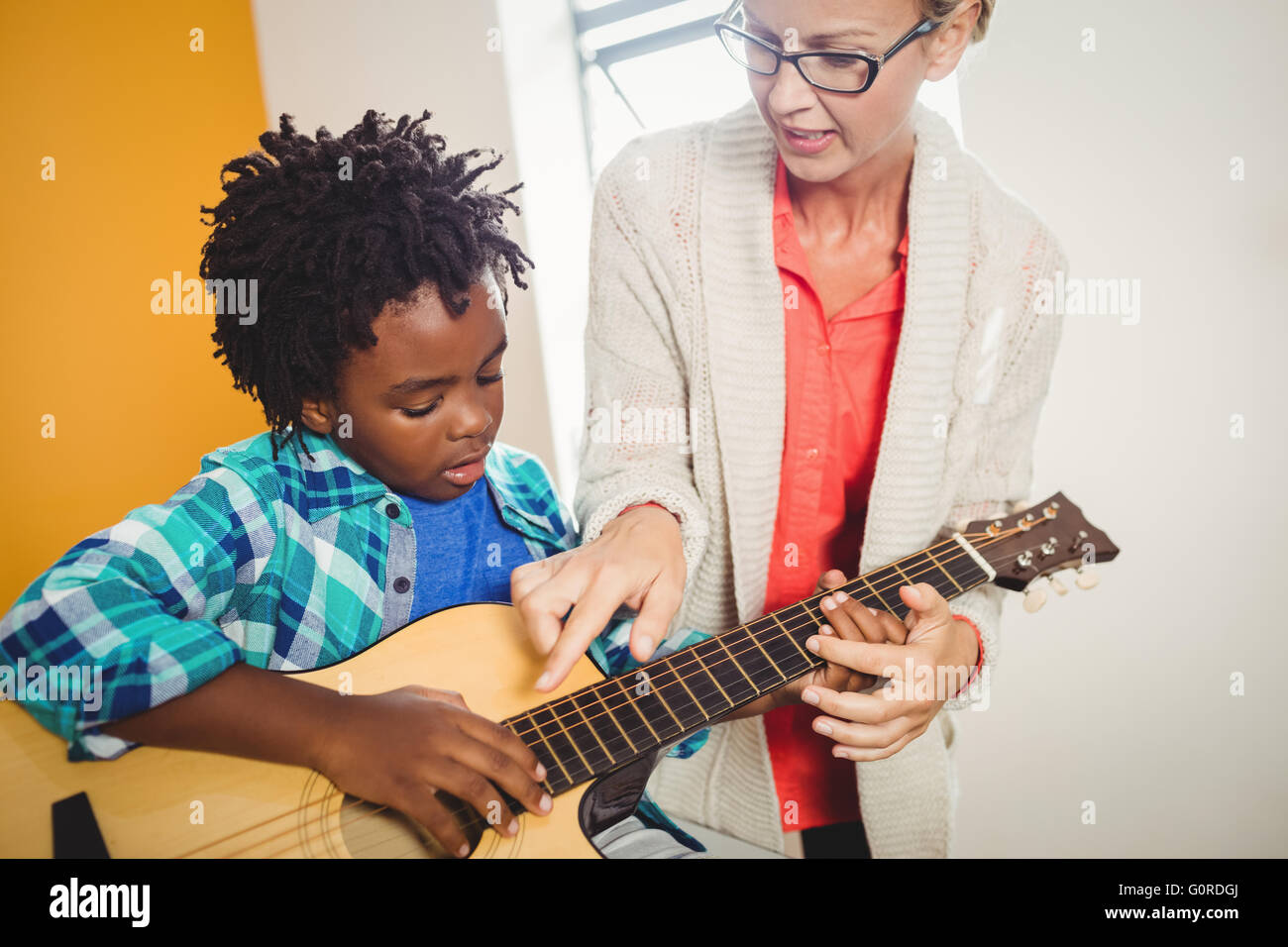 Boy learning how to play the guitar Stock Photo - Alamy