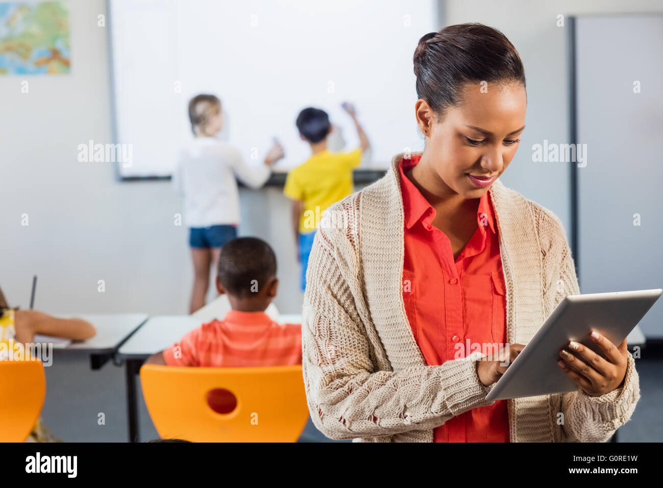 A teacher using tablet while pupils working Stock Photo - Alamy