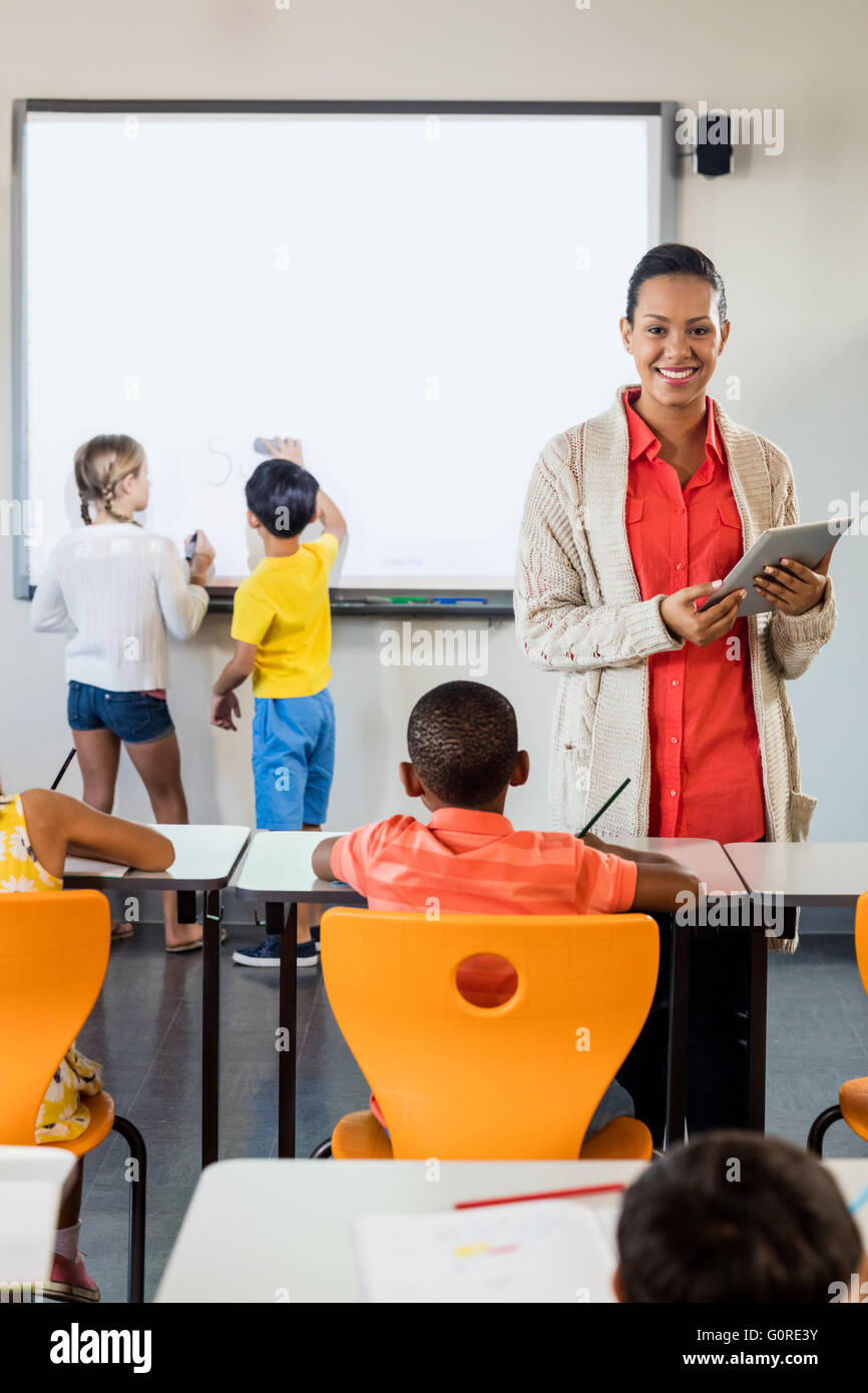 Smiling teacher posing with tablet pc in classroom Stock Photo - Alamy