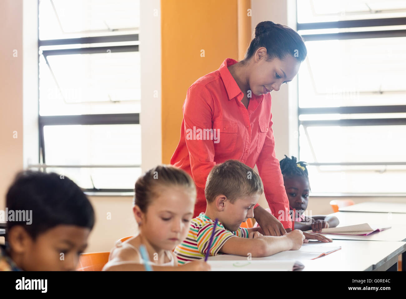 A teacher helping pupils in classroom Stock Photo - Alamy