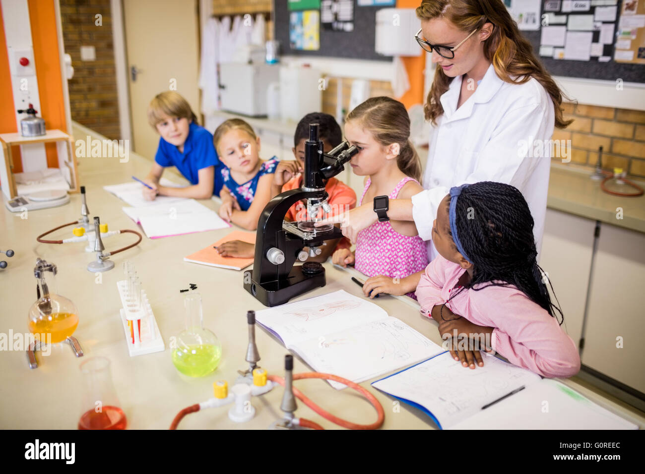Teacher giving lesson to her students Stock Photo - Alamy