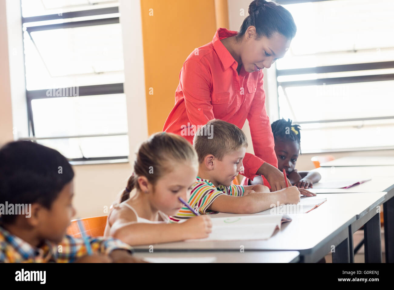 Teacher giving lesson to her students Stock Photo - Alamy