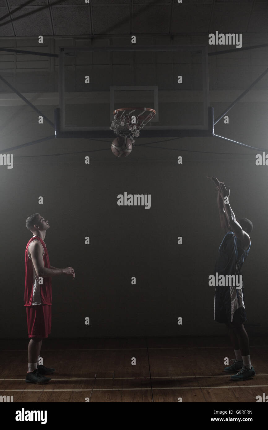 Two basketball player in a gymnasium with one scoring a shoot Stock ...
