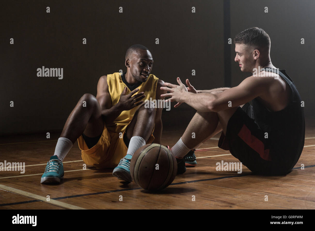 Basketball players sitting on floor talking together Stock Photo - Alamy