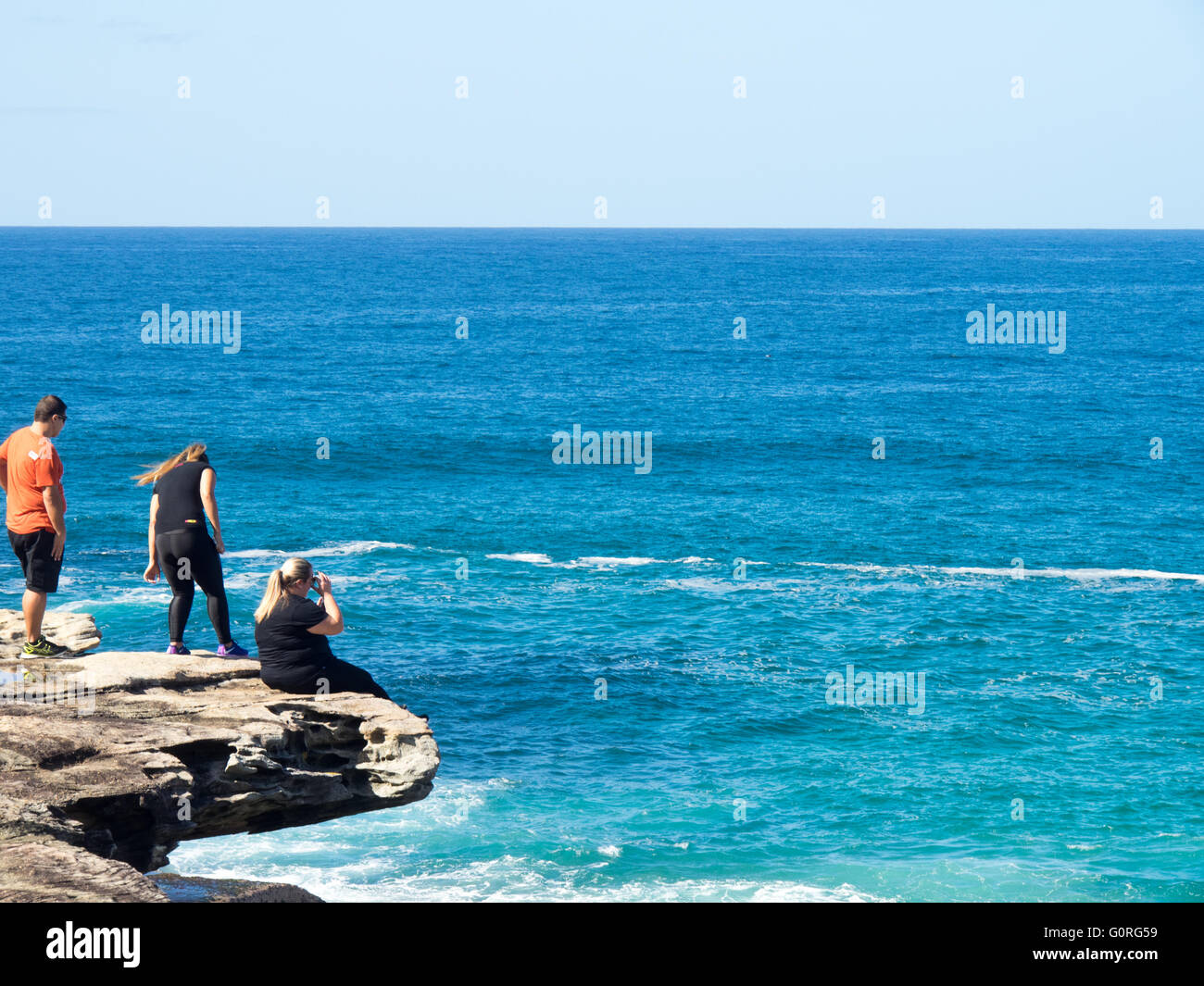 A man and two women on the edge of a rocky ledge overlooking the ...