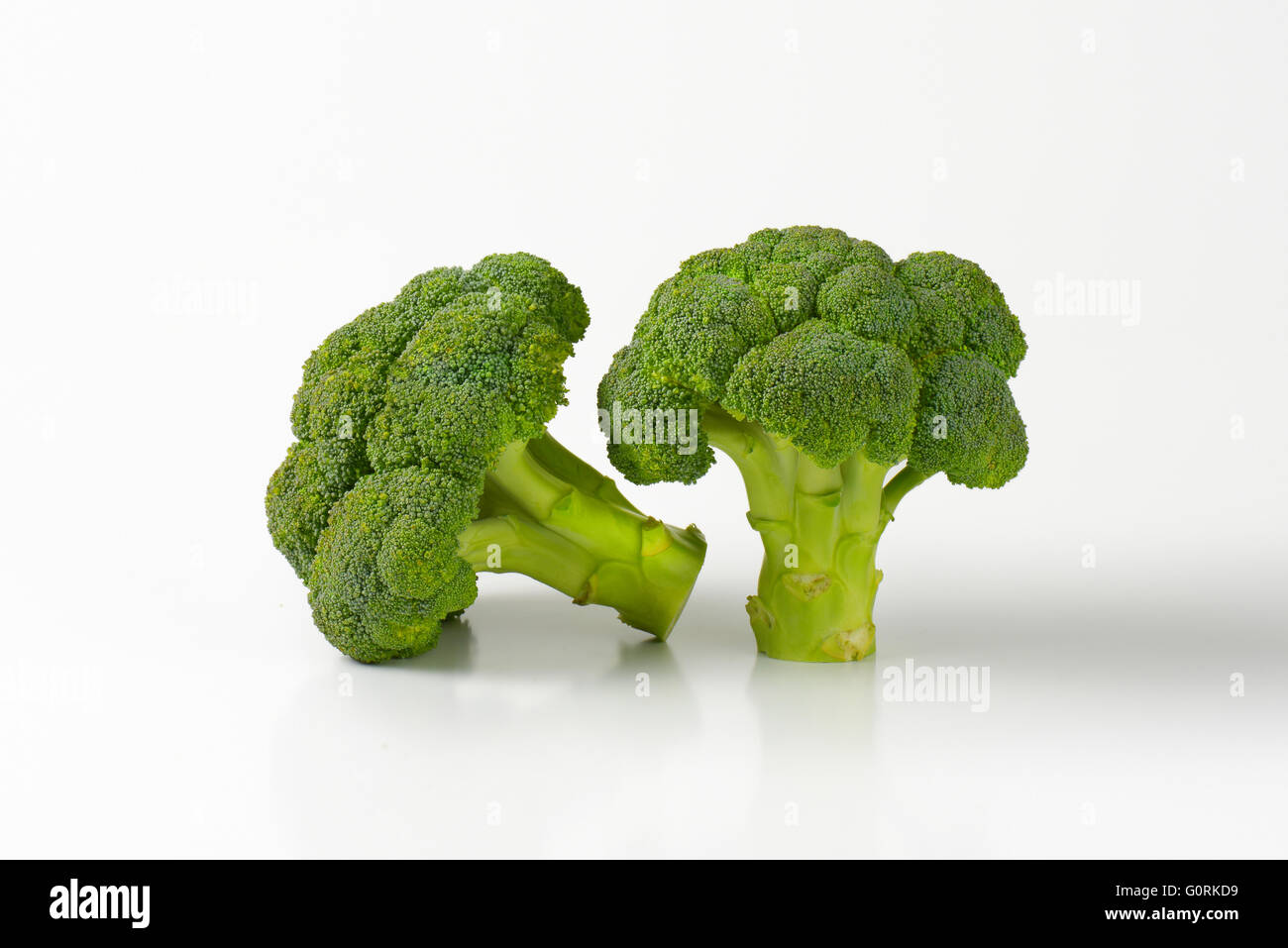 two fresh broccoli heads on off-white background Stock Photo - Alamy