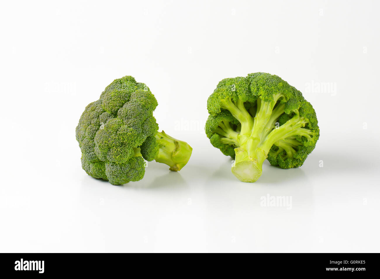 two fresh broccoli heads on off-white background Stock Photo - Alamy