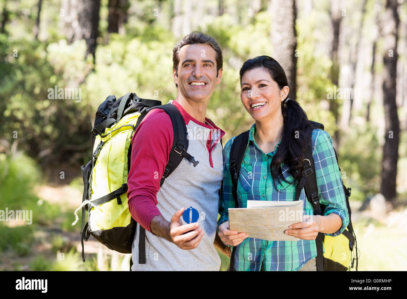 Couple smiling and holding a map and a compass Stock Photo - Alamy