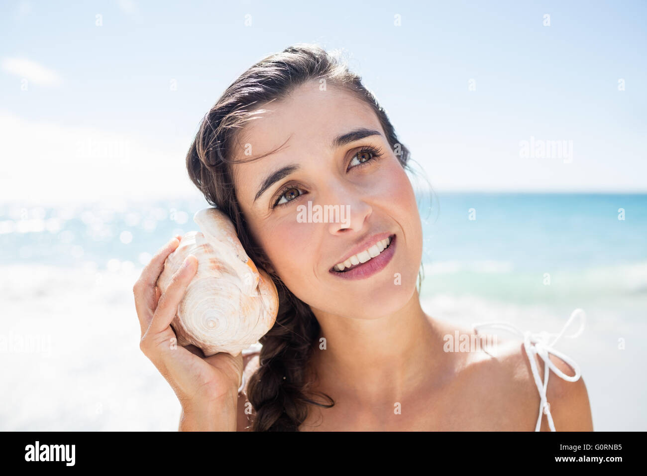 Portrait of smiling woman listening shellfish Stock Photo - Alamy