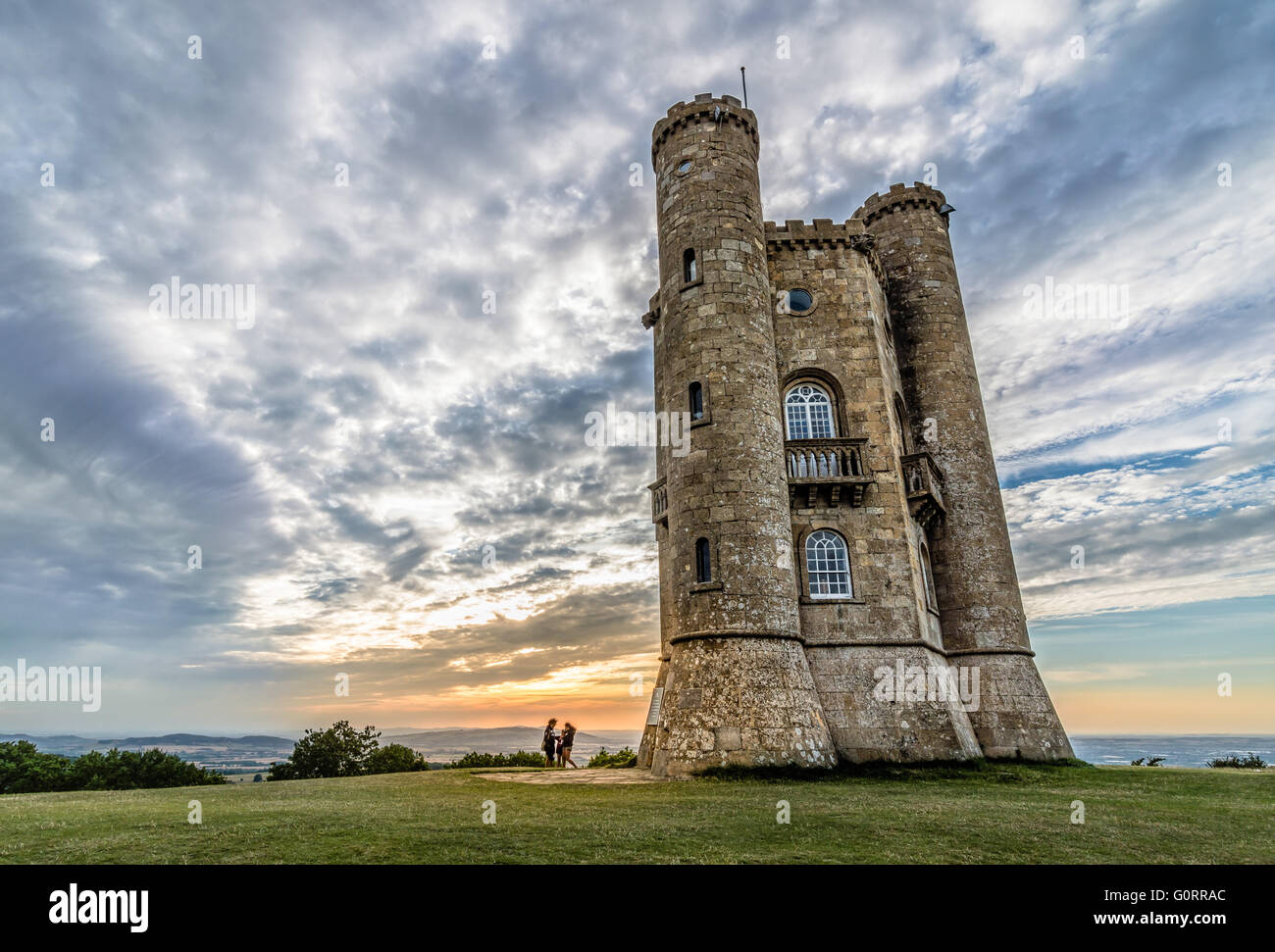Historic english tower at sunset with the silhouette of two people ...